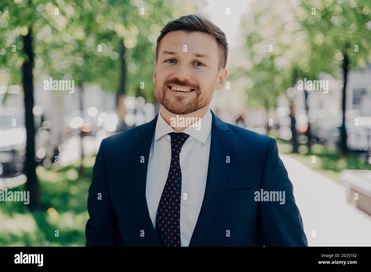 Close portrait of smiling handsome young bearded businessman outdoors ...
