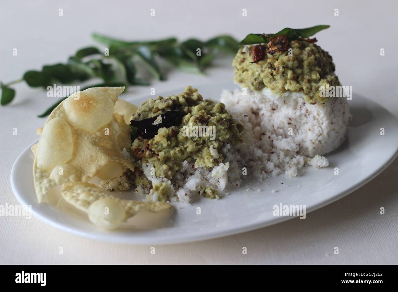Steamed rice cake served with green gram curry and papad. A favorite ...