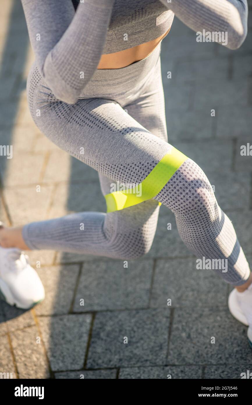 Female sportsperson in grey sportswear exercising with a resistance ...