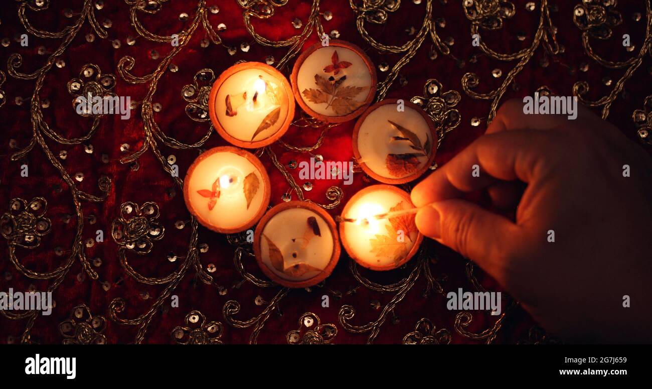 Top view of a hand burning candles with a match on decorative cloth ...