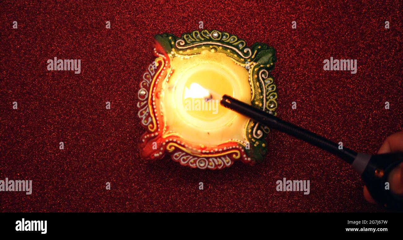 Top view of burning of a candle with a candle lighter on red background ...