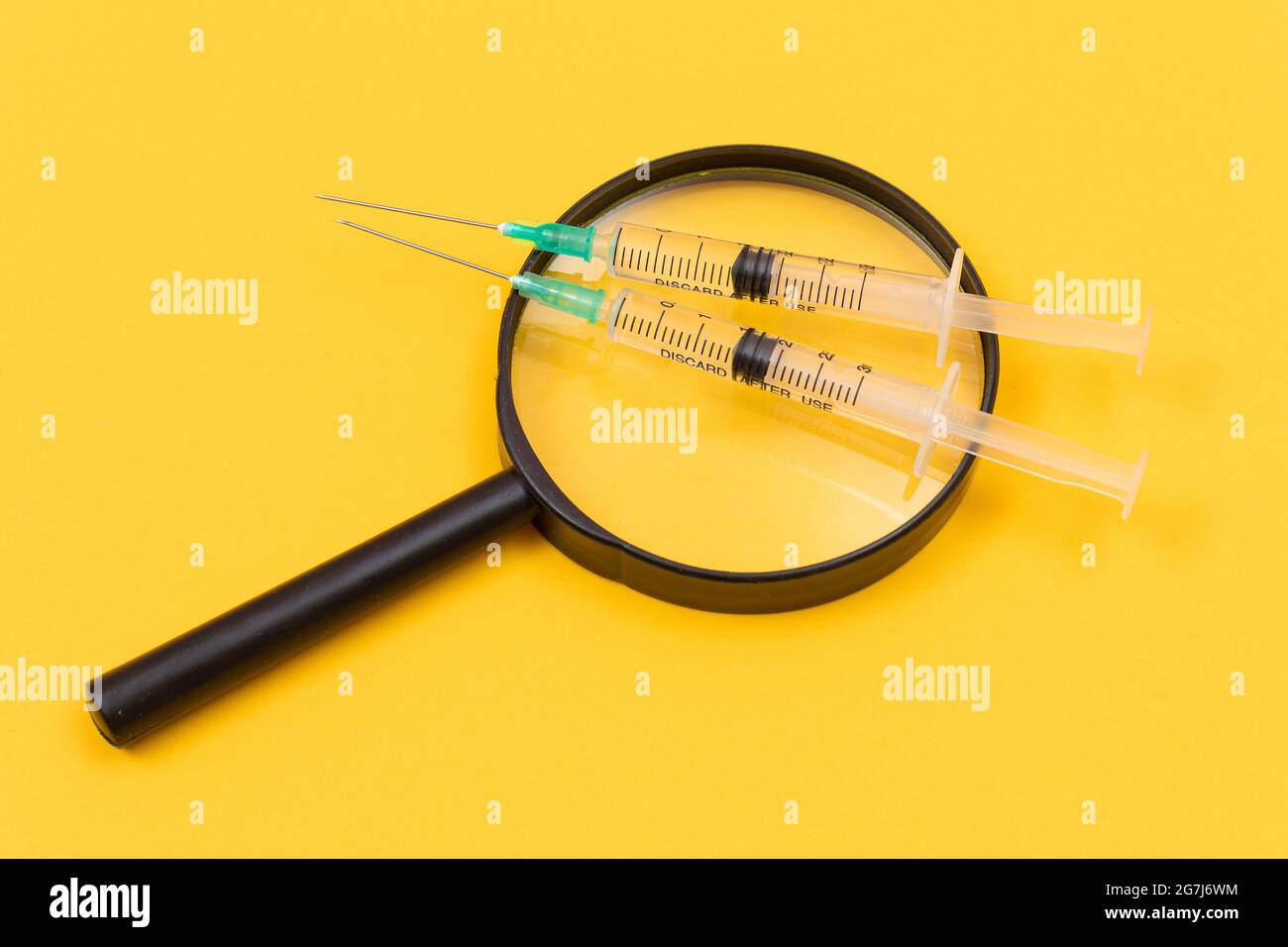 A Magnifier with Medical Syringe Lying on Yellow Table - Vaccination ...