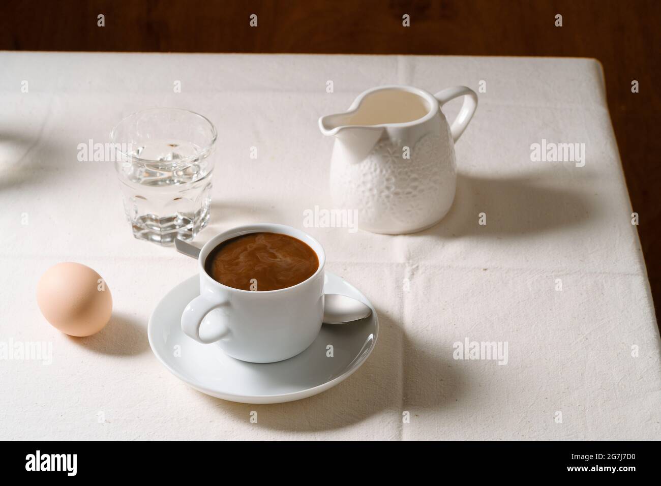 Dining table set for breakfast. Coffee, boiled egg, milk and glass of ...