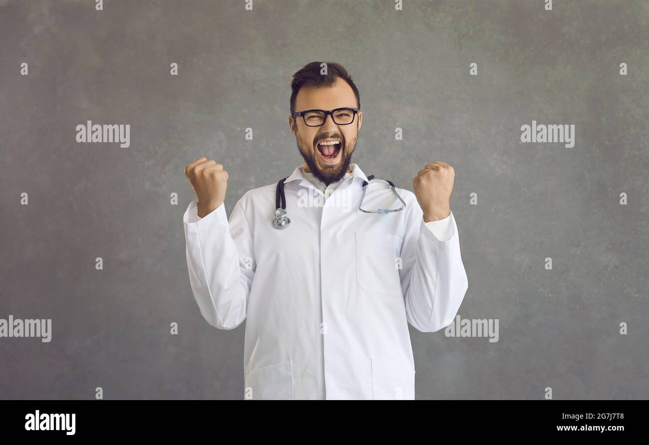 Excited smiling male doctor in medical uniform showing yes hand gesture ...