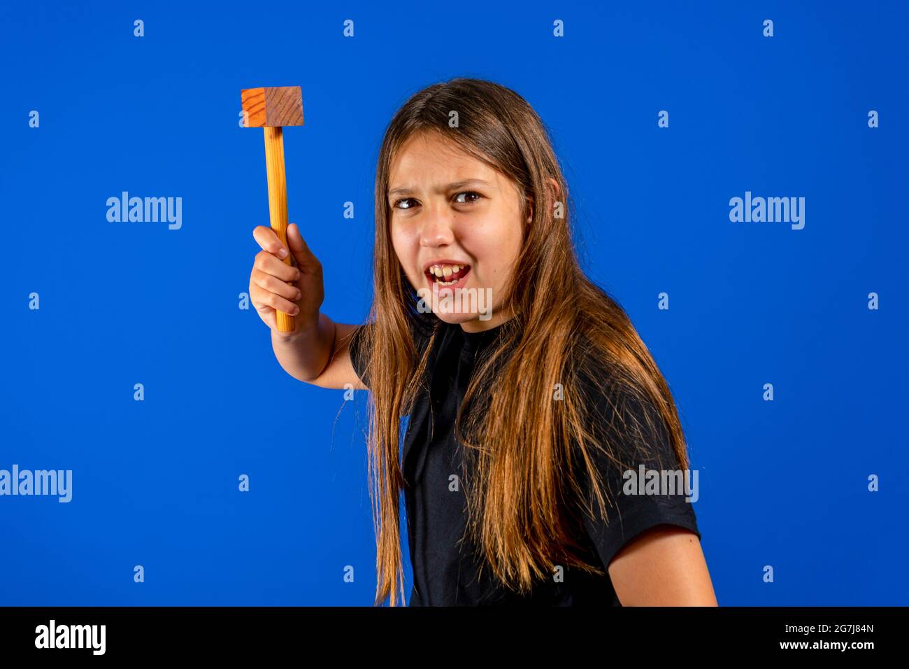 Pretty preteen girl attacking with a wooden kitchen mallet in self ...