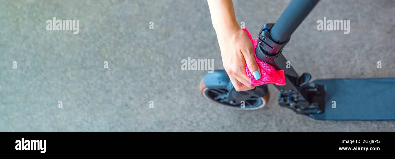 Cleaning or washing the scooter. Electric scooter care. A woman wipes a ...