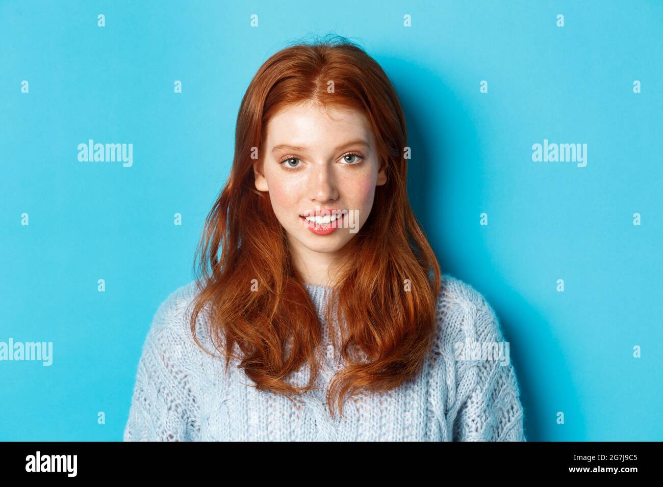 Close-up of young cute redhead girl smiling at camera, standing against ...