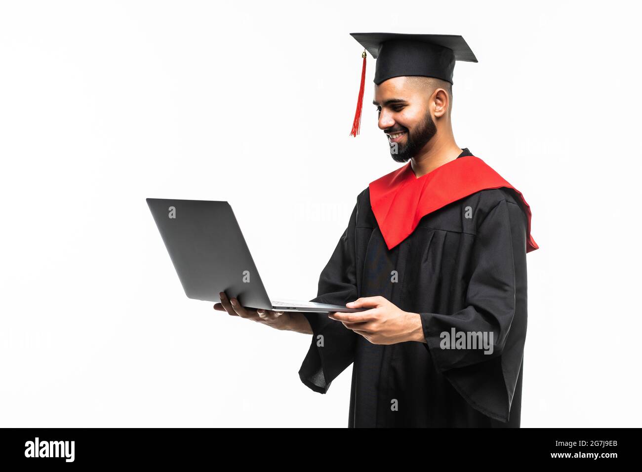 Male graduate holding a laptop computer and smiling at the camera ...