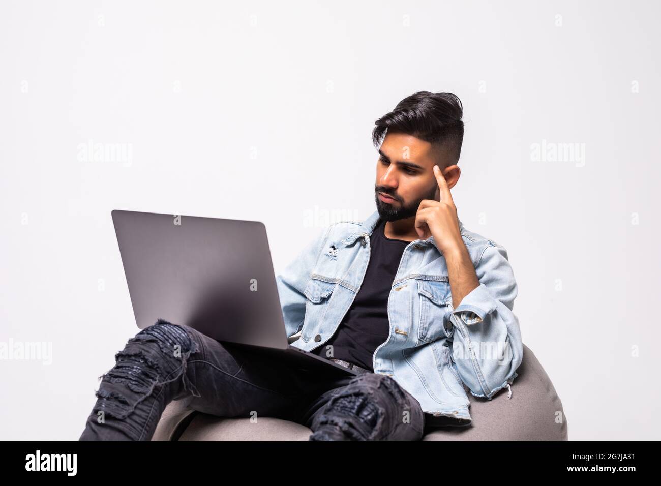 A young man sitting on the floor with a crossed legs putting his laptop ...