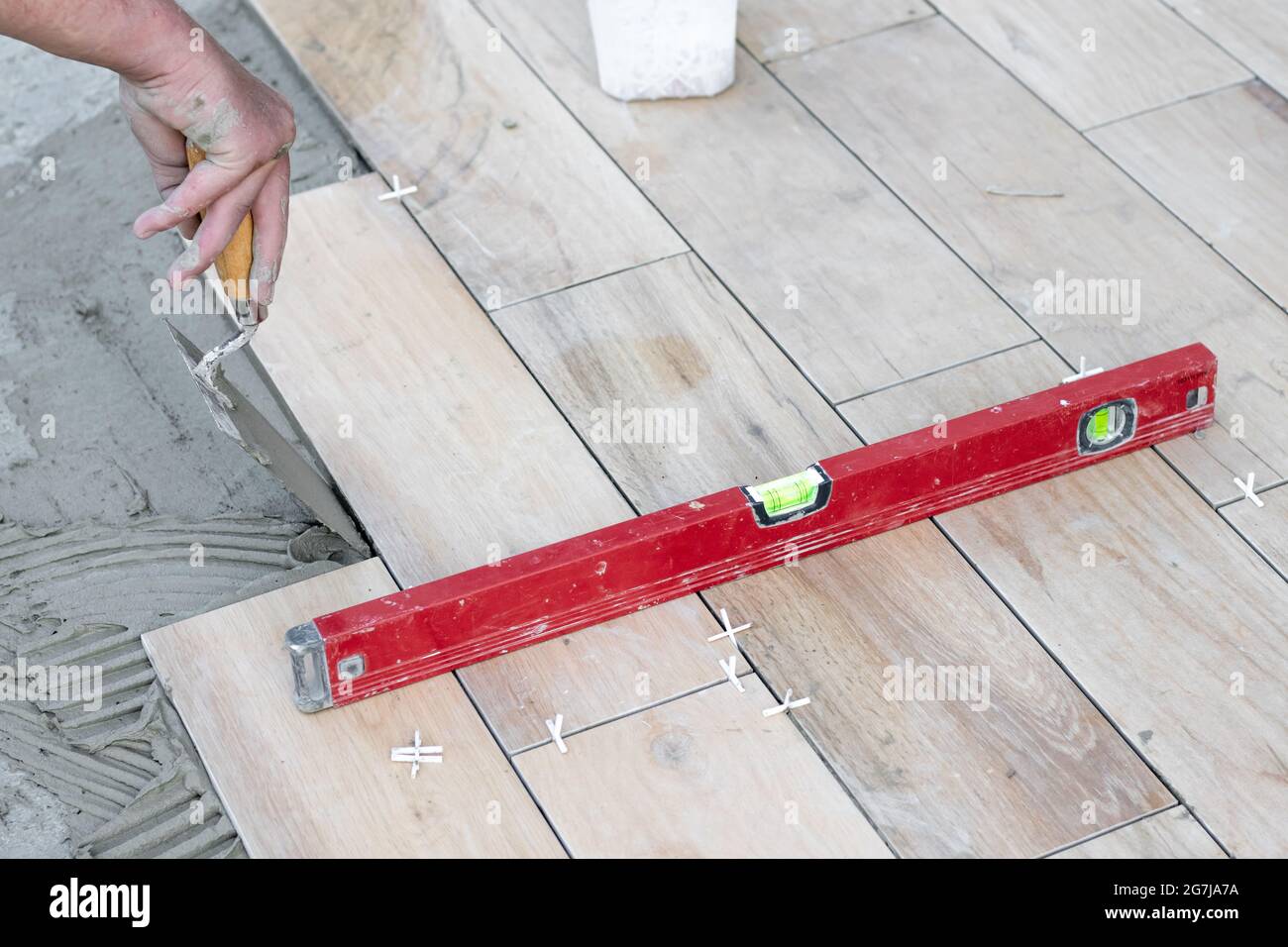 The hands of the tiler lying or installing modern, ceramic tile above ...