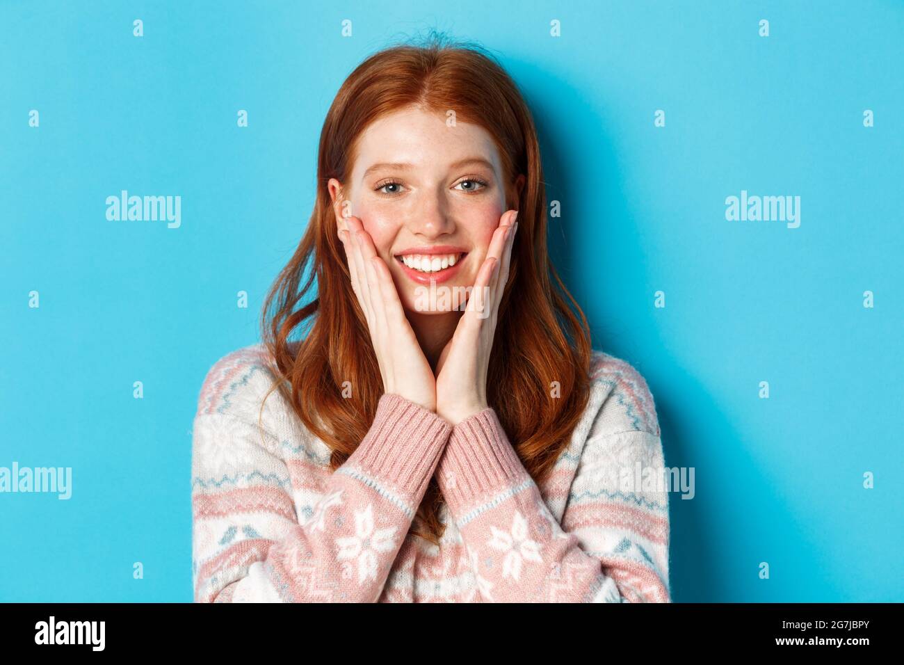 Close-up of cheerful redhead girl blushing, touching cheeks and smiling ...