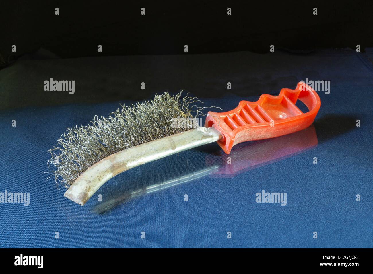 An old wire brush with a red handle on the table. Working tool on a ...