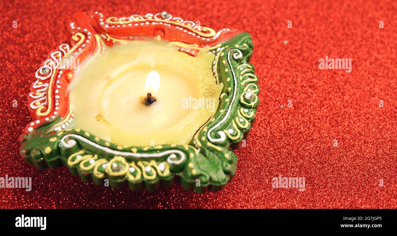 Ornamented Indian-style candlestick base on the red surface; Divali ...