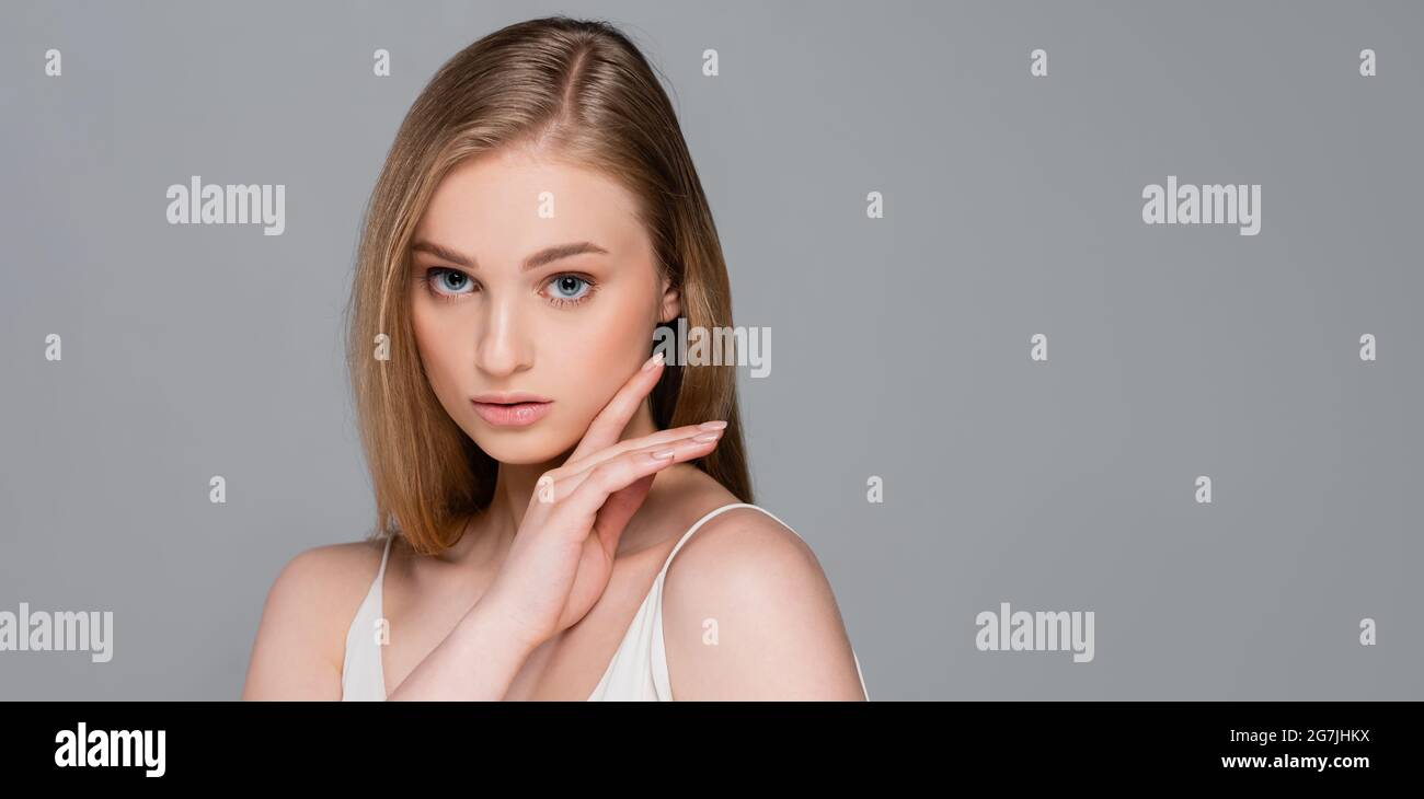 pretty young woman with makeup looking at camera isolated on gray ...