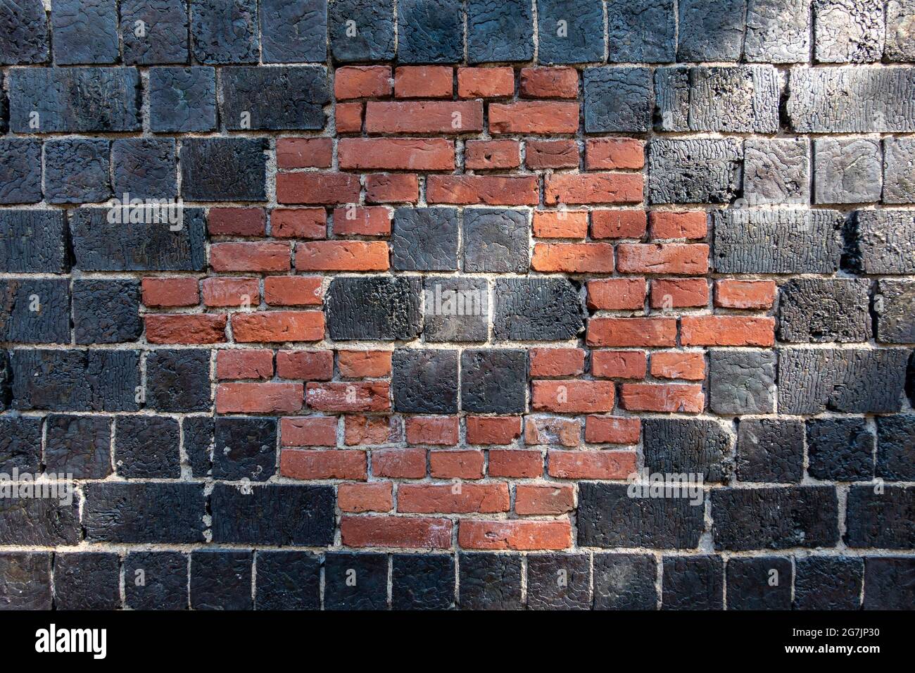 Red brick pattern on the black slag brick wall of an old mill in ...