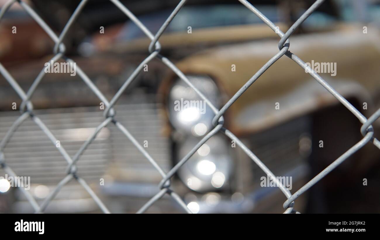 Rusty old car visible through a gate in a junkyard Stock Photo - Alamy