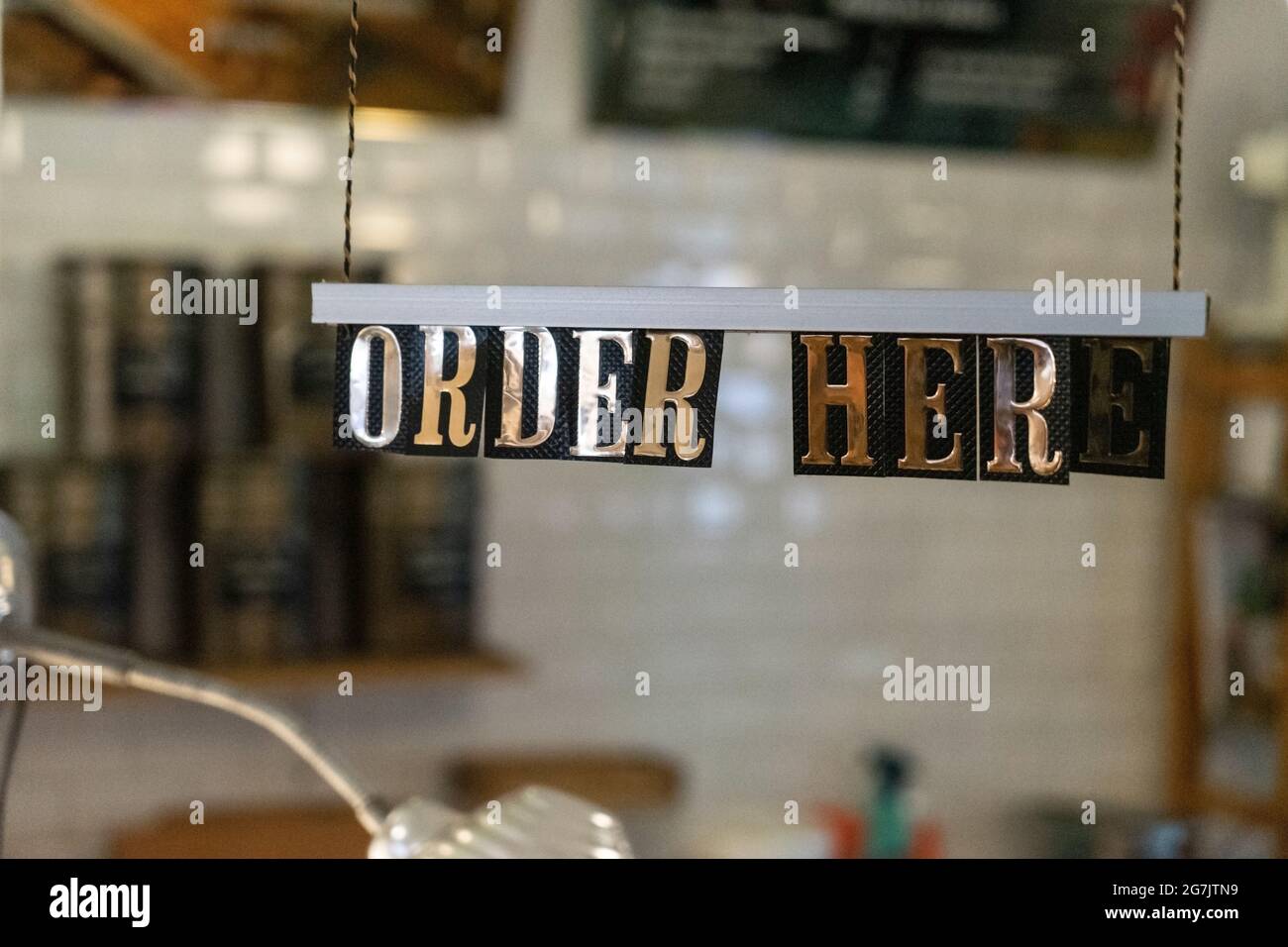 Golden Order Here sign at a cashier of a coffee shop Stock Photo - Alamy