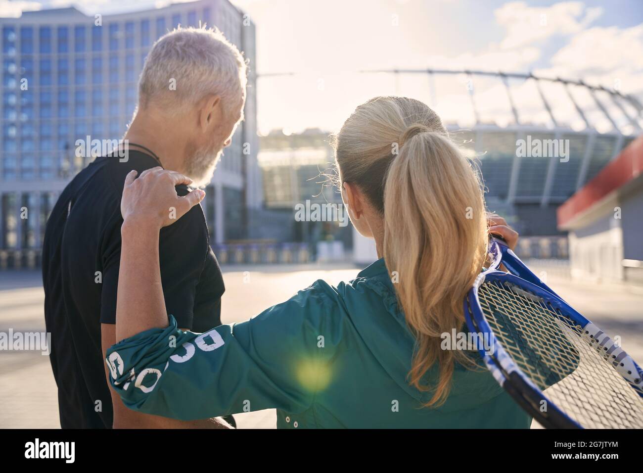 Back view of sportive middle aged couple, tennis players with tennis ...