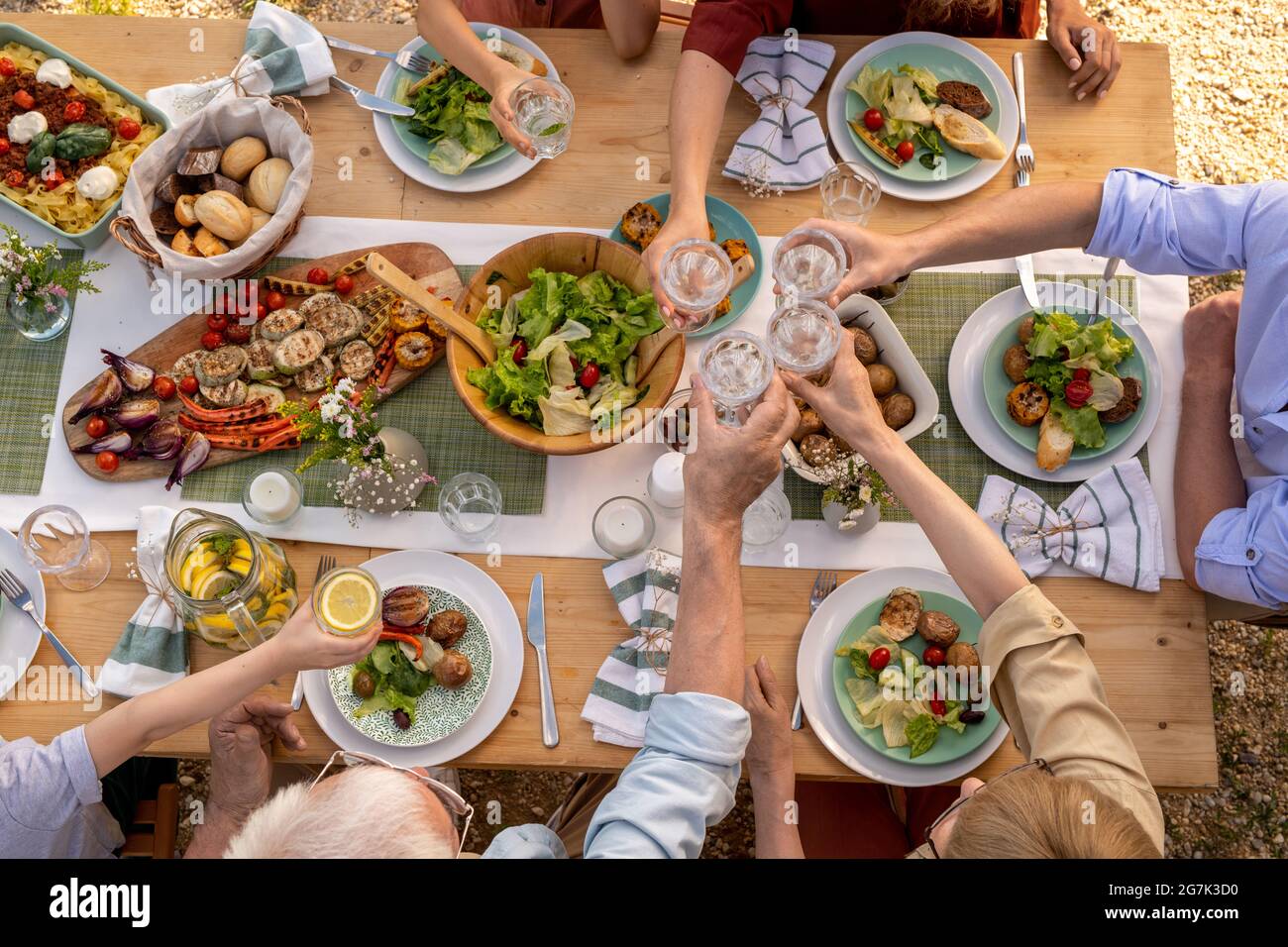 Group of people toasting with glasses of fresh water over dinner table ...