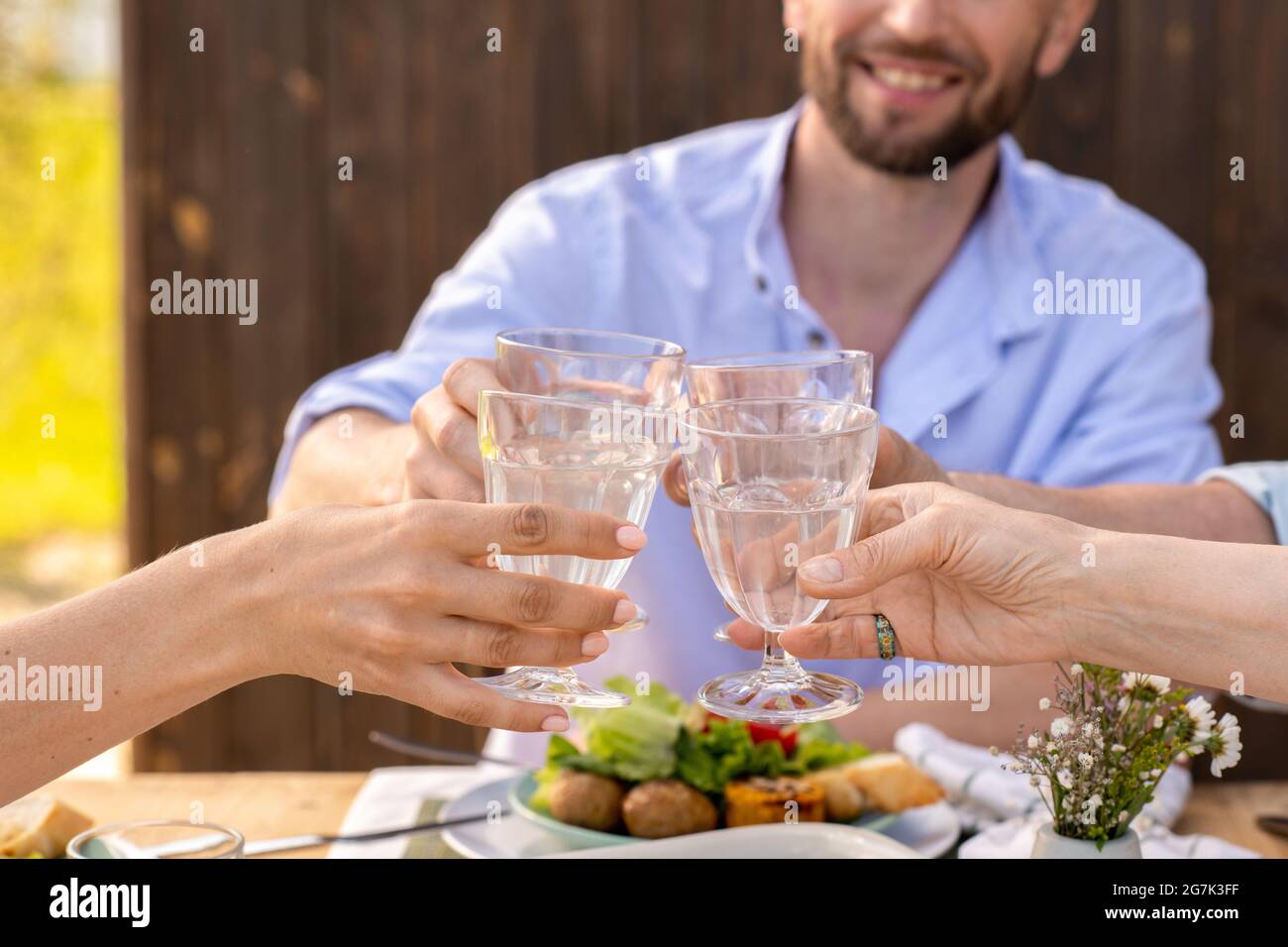 Hands of friend toasting with glasses over dinner table at birthday ...