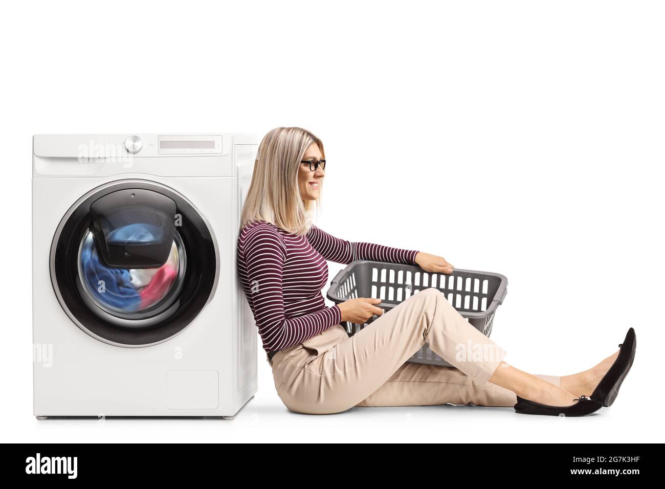 Woman with a laundry basket sitting and leaning on a washing machine ...