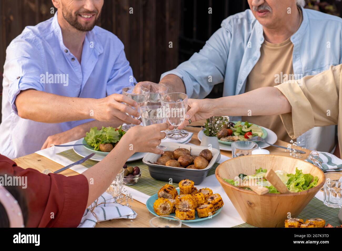 Family members toasting with glasses of cold beverages over dinner ...