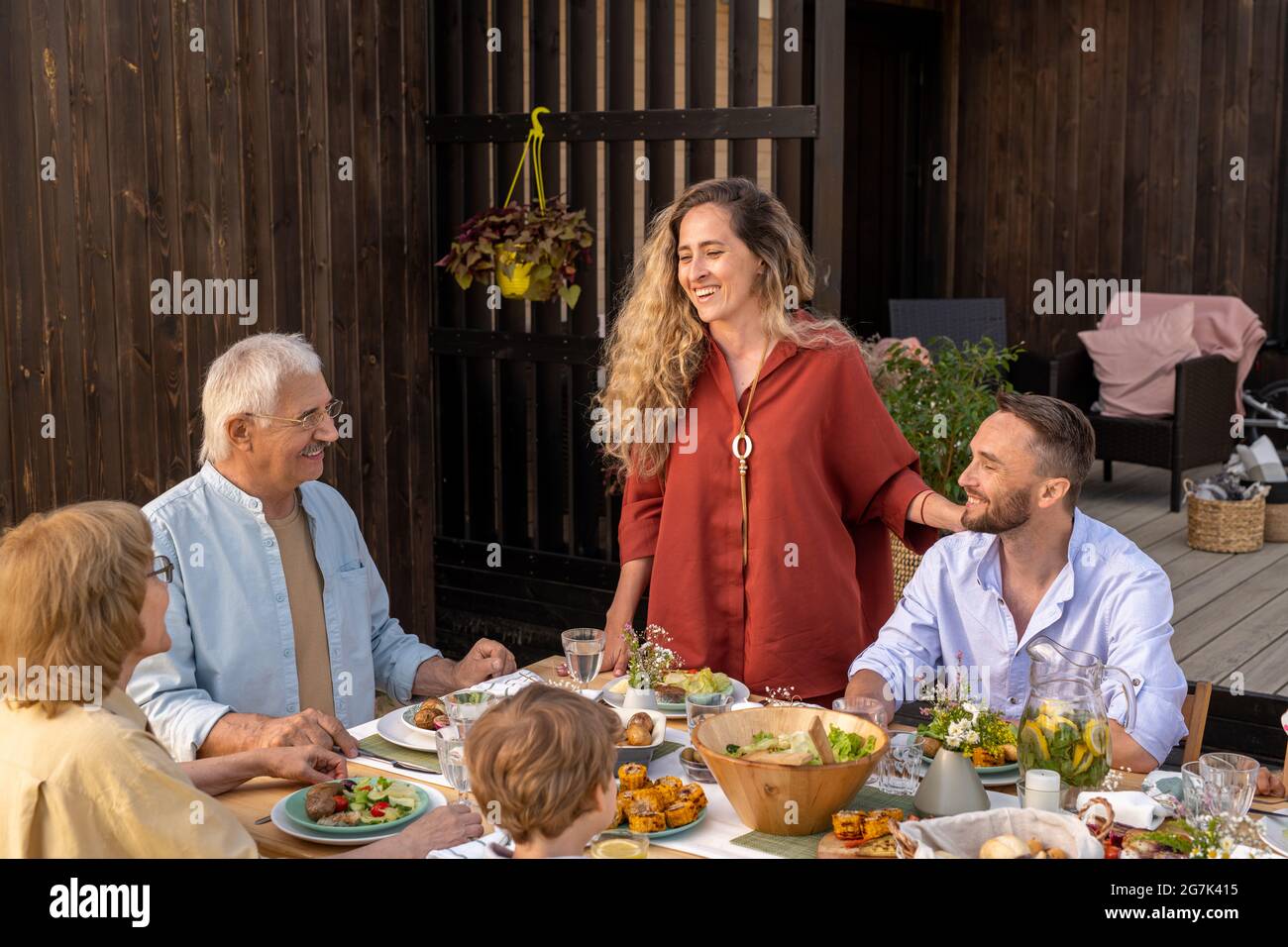 Beautiful young woman with long curly hair giving toast at dinner party ...