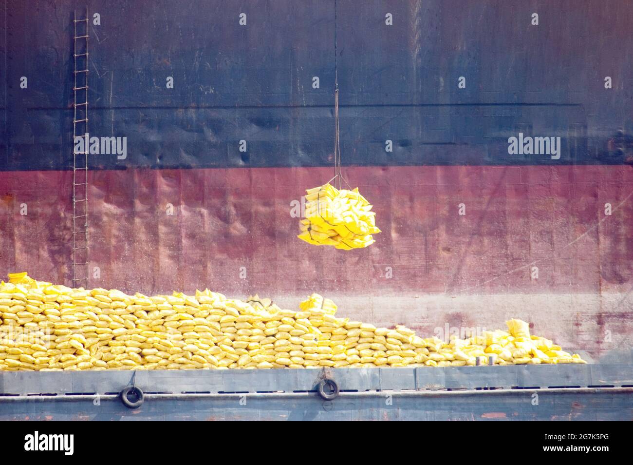 Closeup of loading goods in a large cargo ship from a small vessel ...