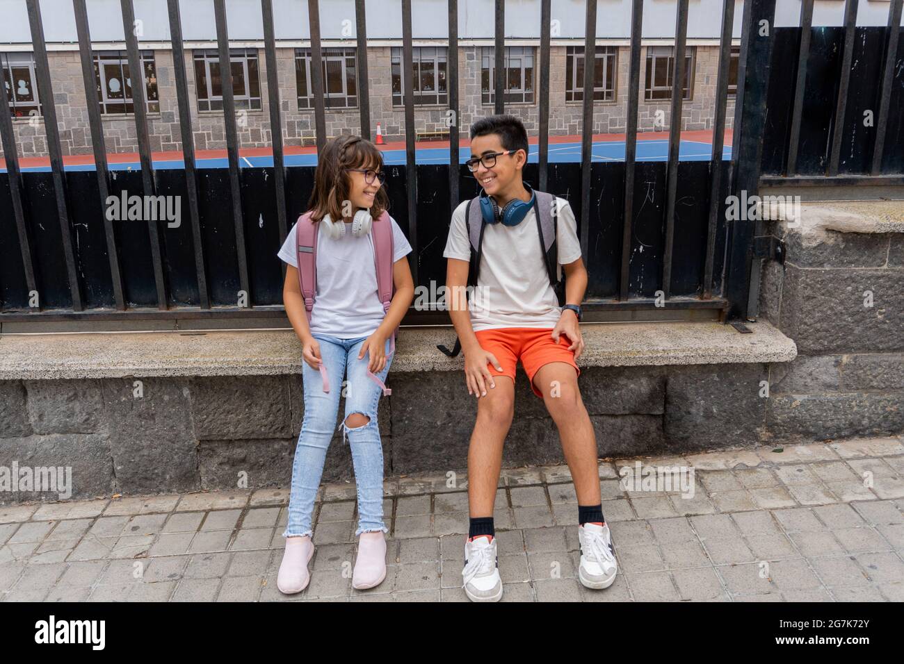 Two Caucasian boys laughing and talking at the school gate. Back to ...