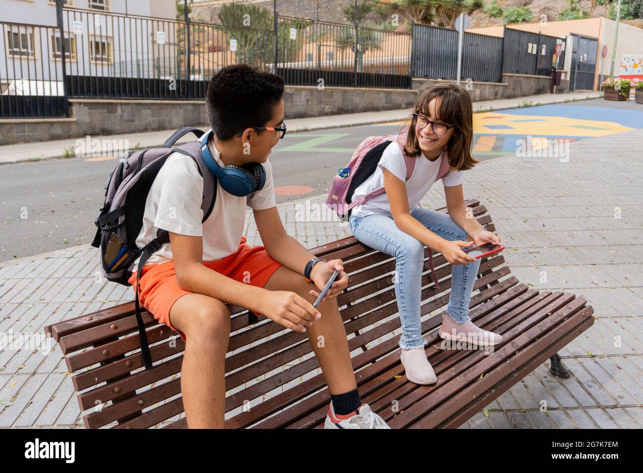 Two Caucasian classmates waiting together for the school bus while ...