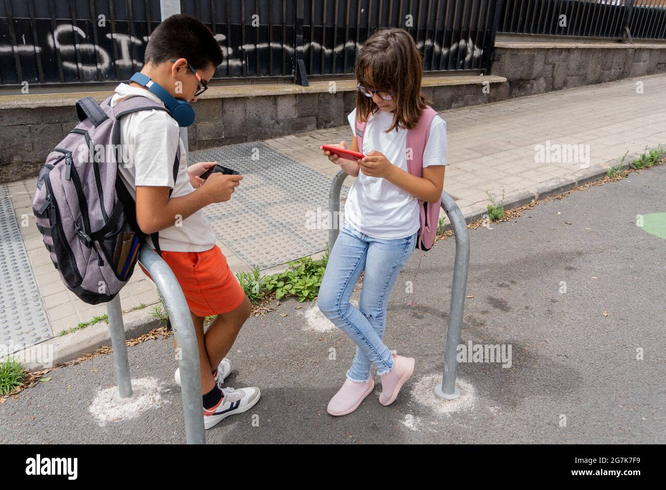 Two Caucasian classmates waiting together for the school bus while ...