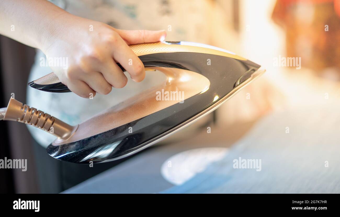 Female hand ironing clothes on iron board at home on the laundry day ...