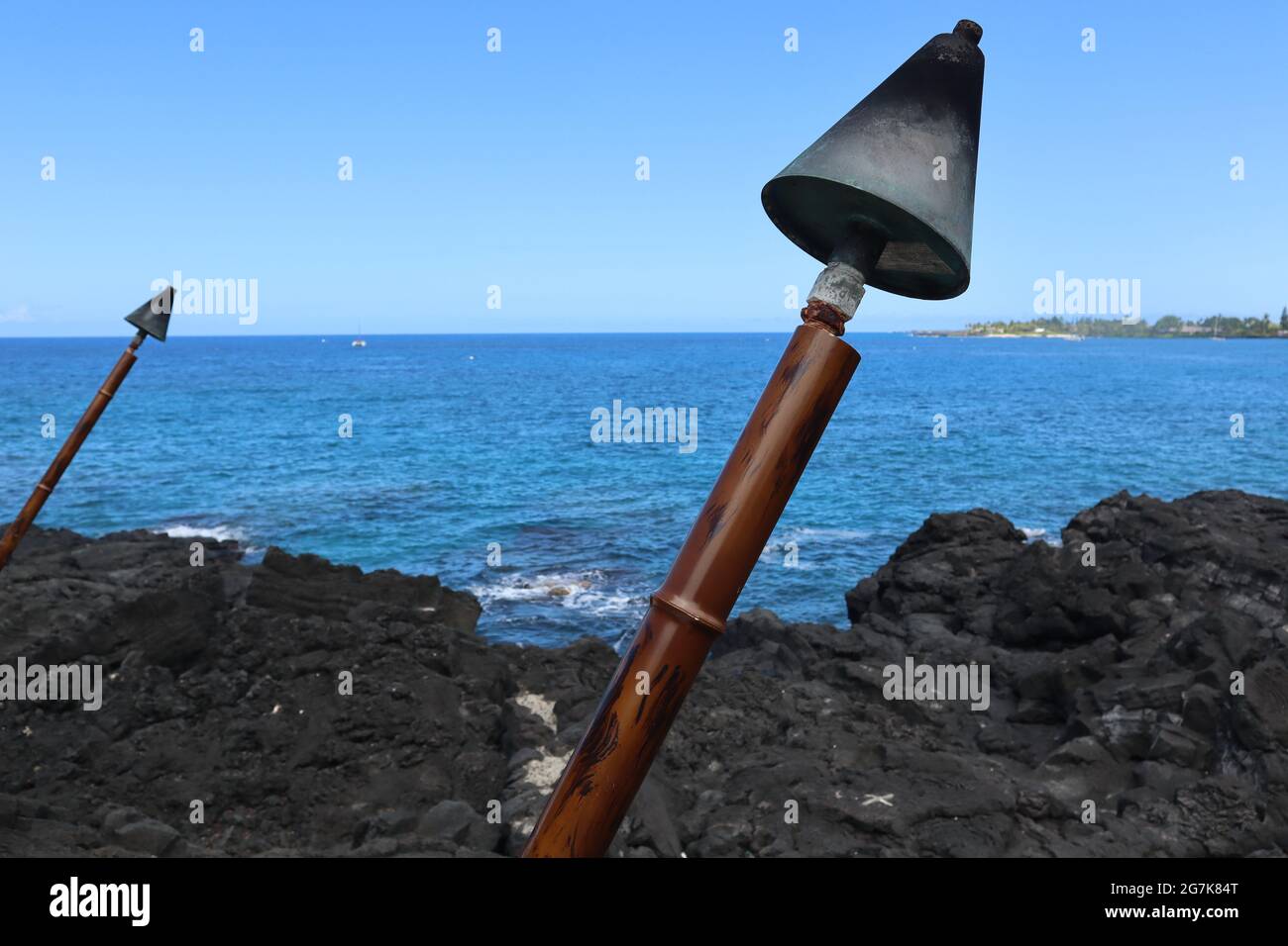 Tiki torch with black volcanic rock and blue ocean landscape at a ...