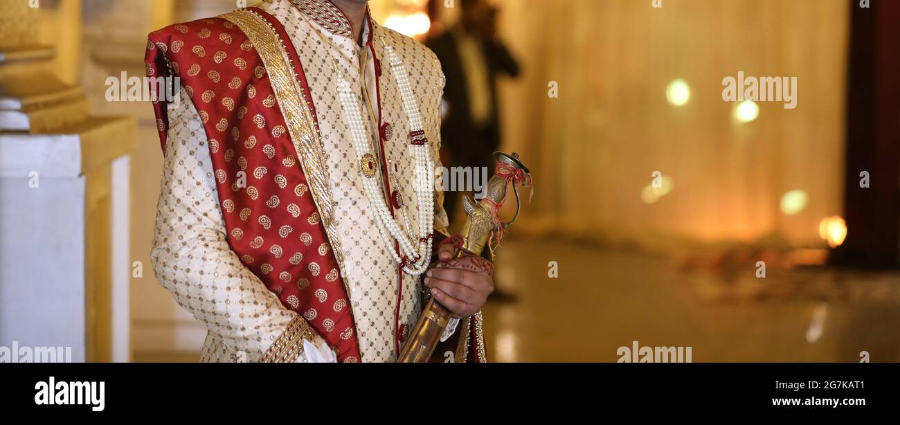 Groom in a traditional wedding dress with Sherwani with sword in hand ...
