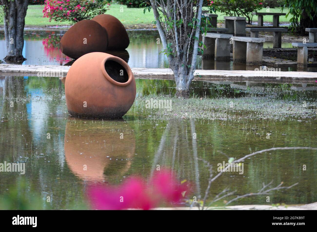 Decorative big clay amphora in the pond surrounded by greens in the ...