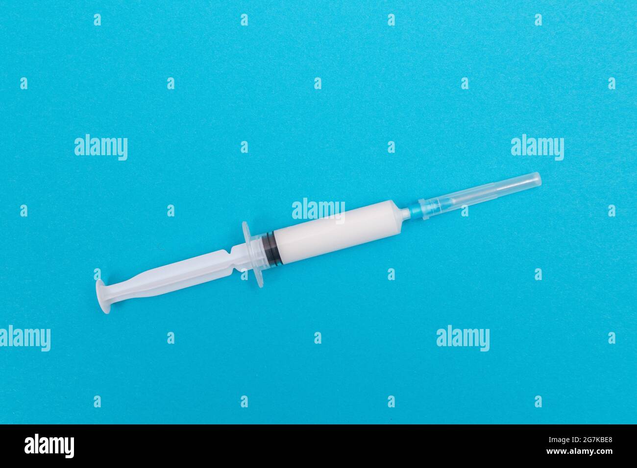 A Syringe with White Liquid Inside on Blue Table. Disposable Plastic ...