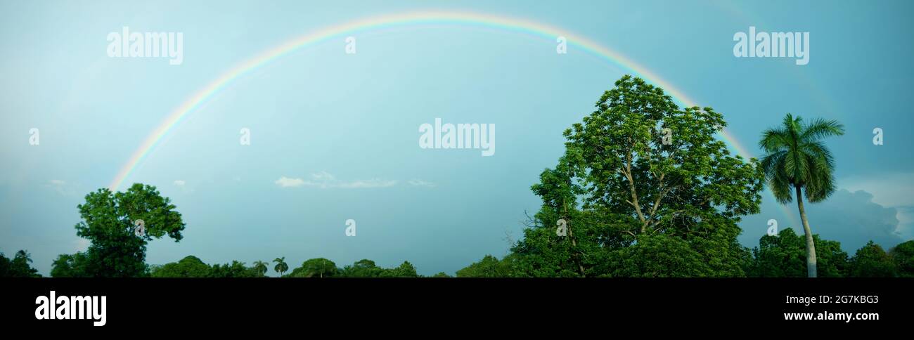 Panoramic shot of the beautiful rainbow over the landscape against the ...