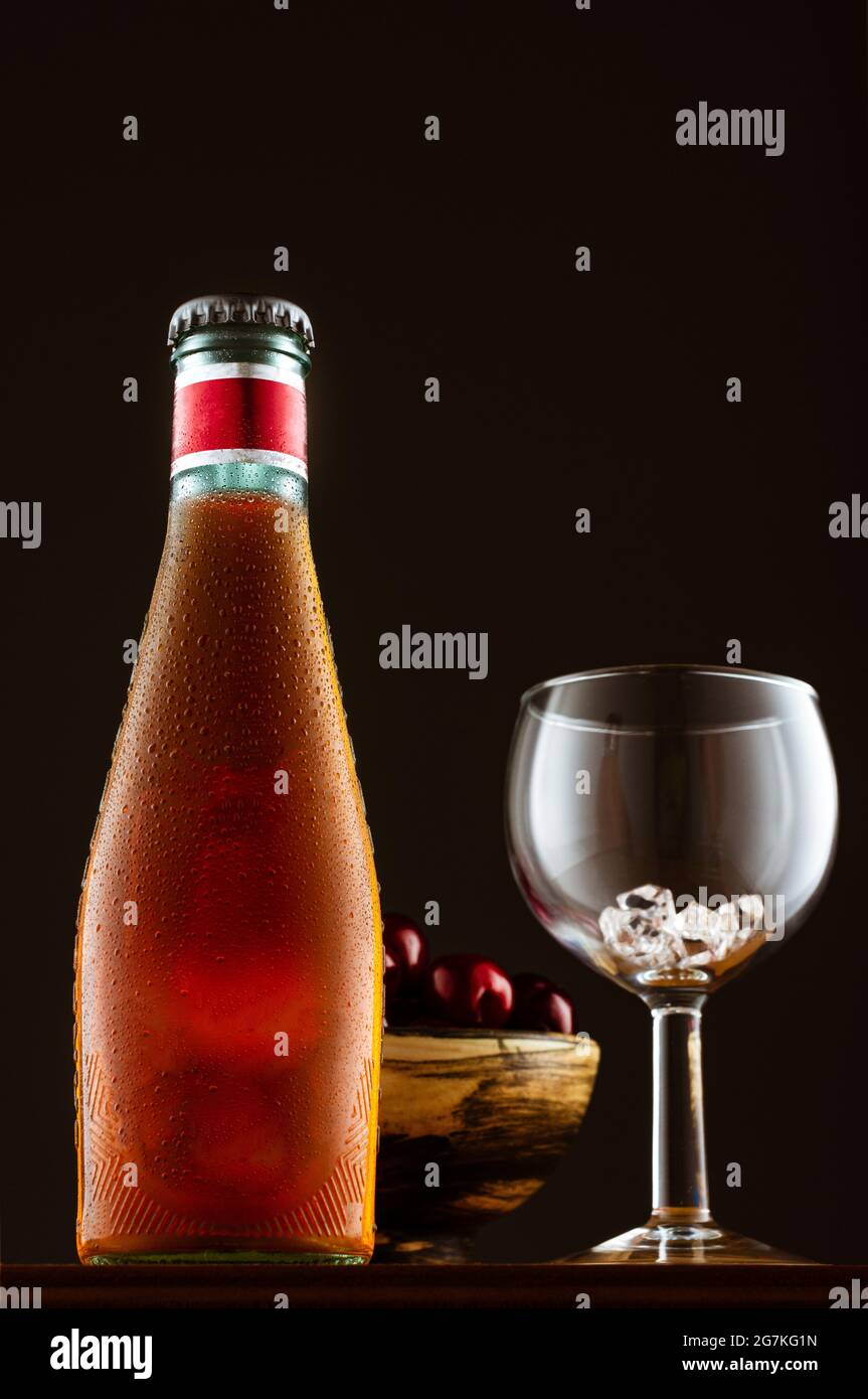 Vertical image of a glass bottle filled with orange alcoholic drink ...