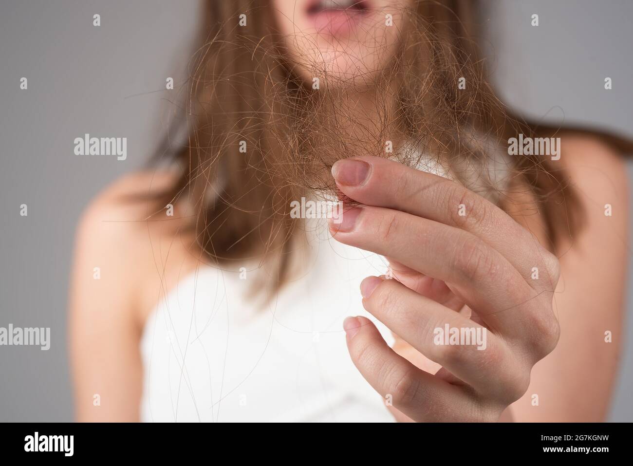 Sad woman looking at damaged hair, the hair loss problem. Studio ...
