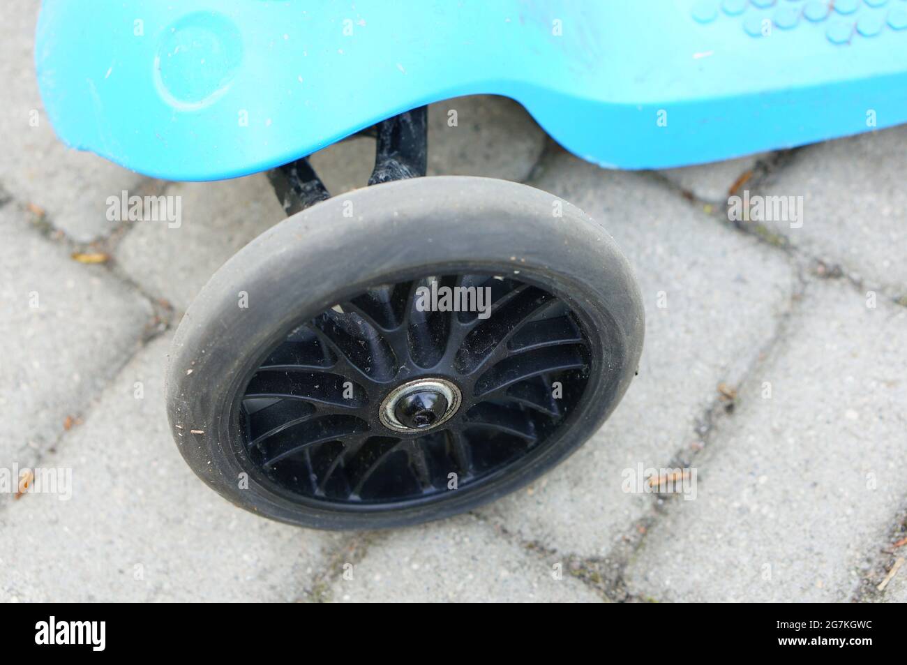 Closeup of a blue kick scooter wheel on the cobblestones in the ...