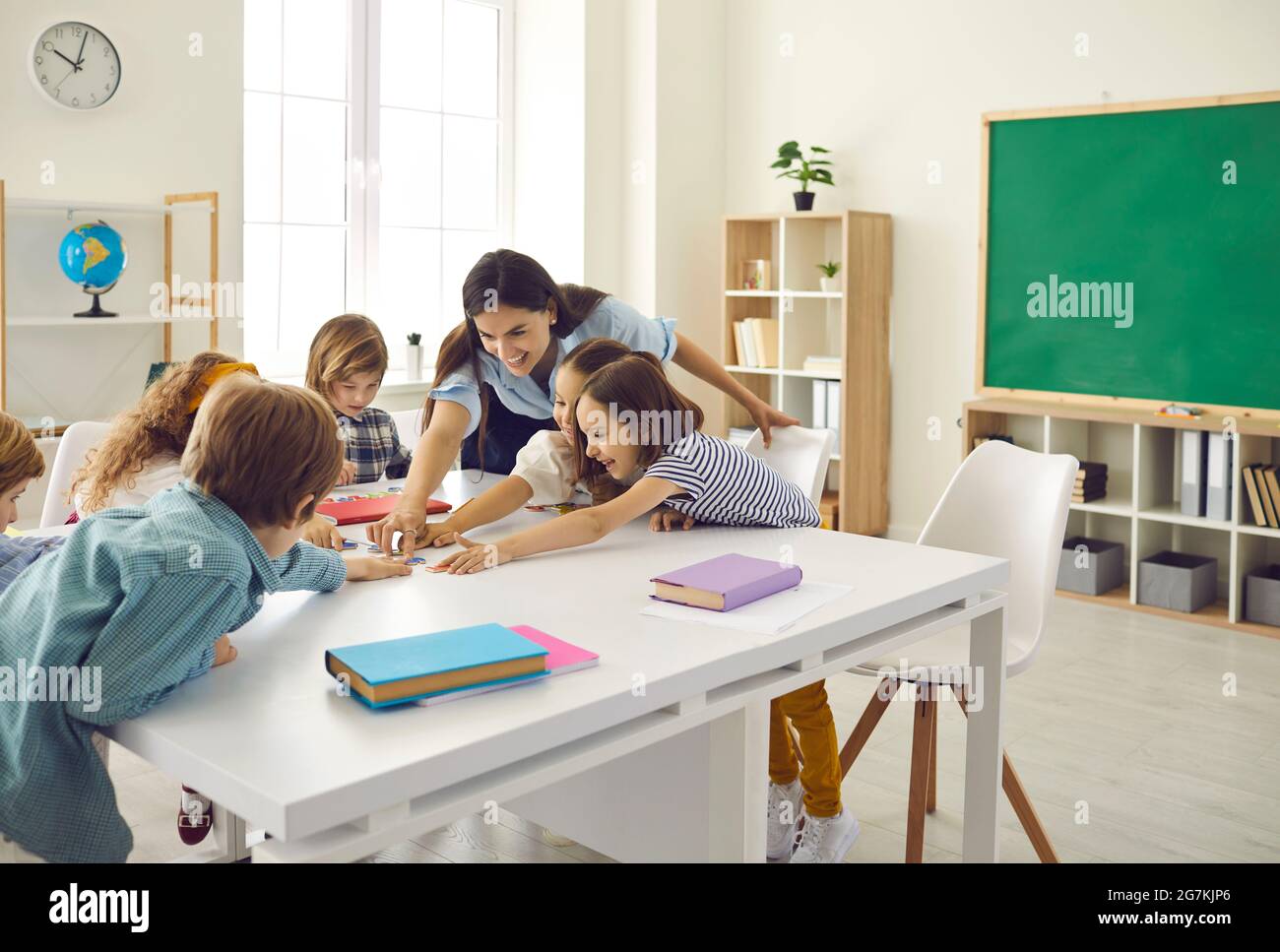 Female teacher and junior students having fun in class putting together ...