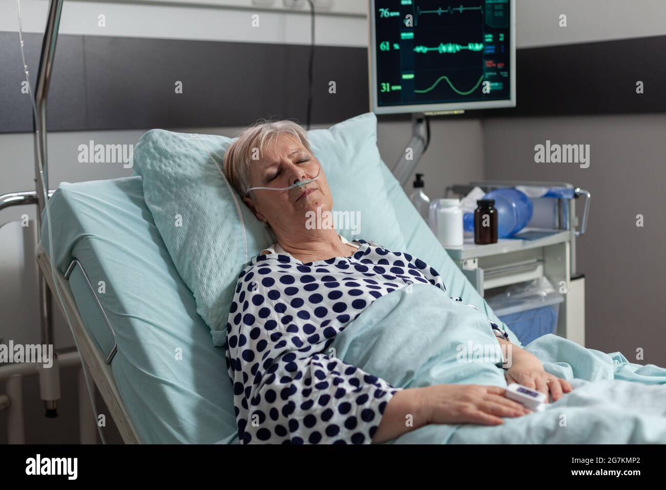 Elderly patient following recovery treatment laying in hospital bed ...
