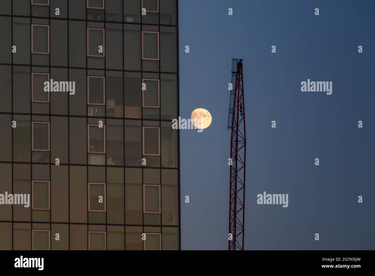 Full moon in the evening sky between the crane and the building Stock ...