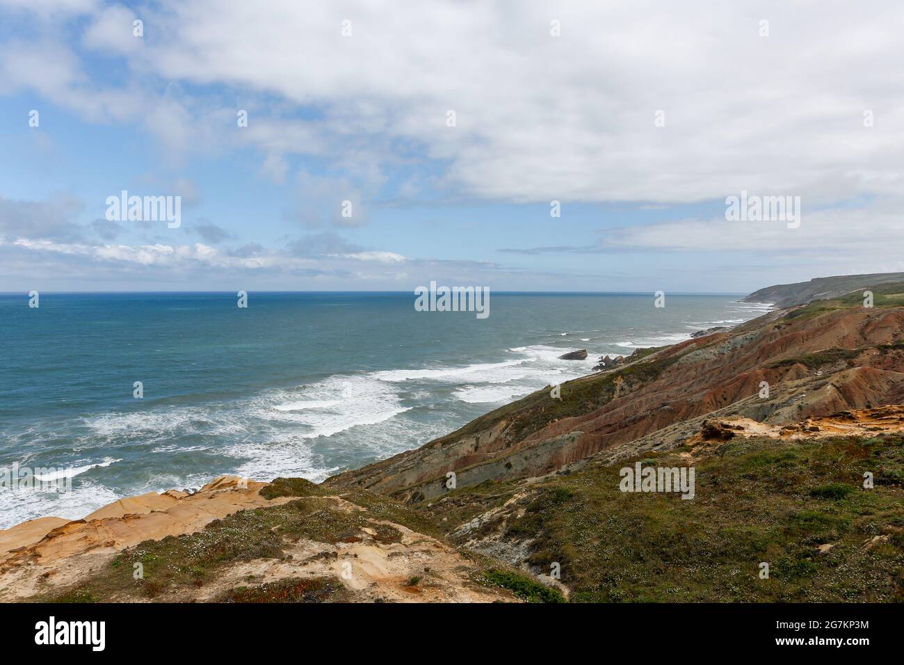 Green rocky edge of a cliff facing the blue ocean Stock Photo - Alamy