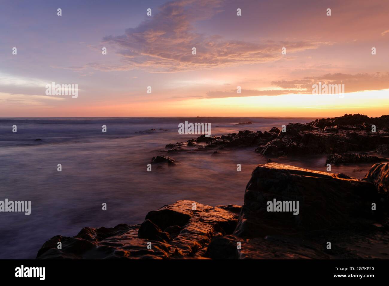 Beautiful sunset on the beach with rocks Stock Photo - Alamy