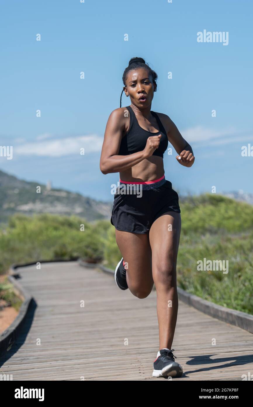 Afro american woman running fast along a wooden runway: Exercise ...