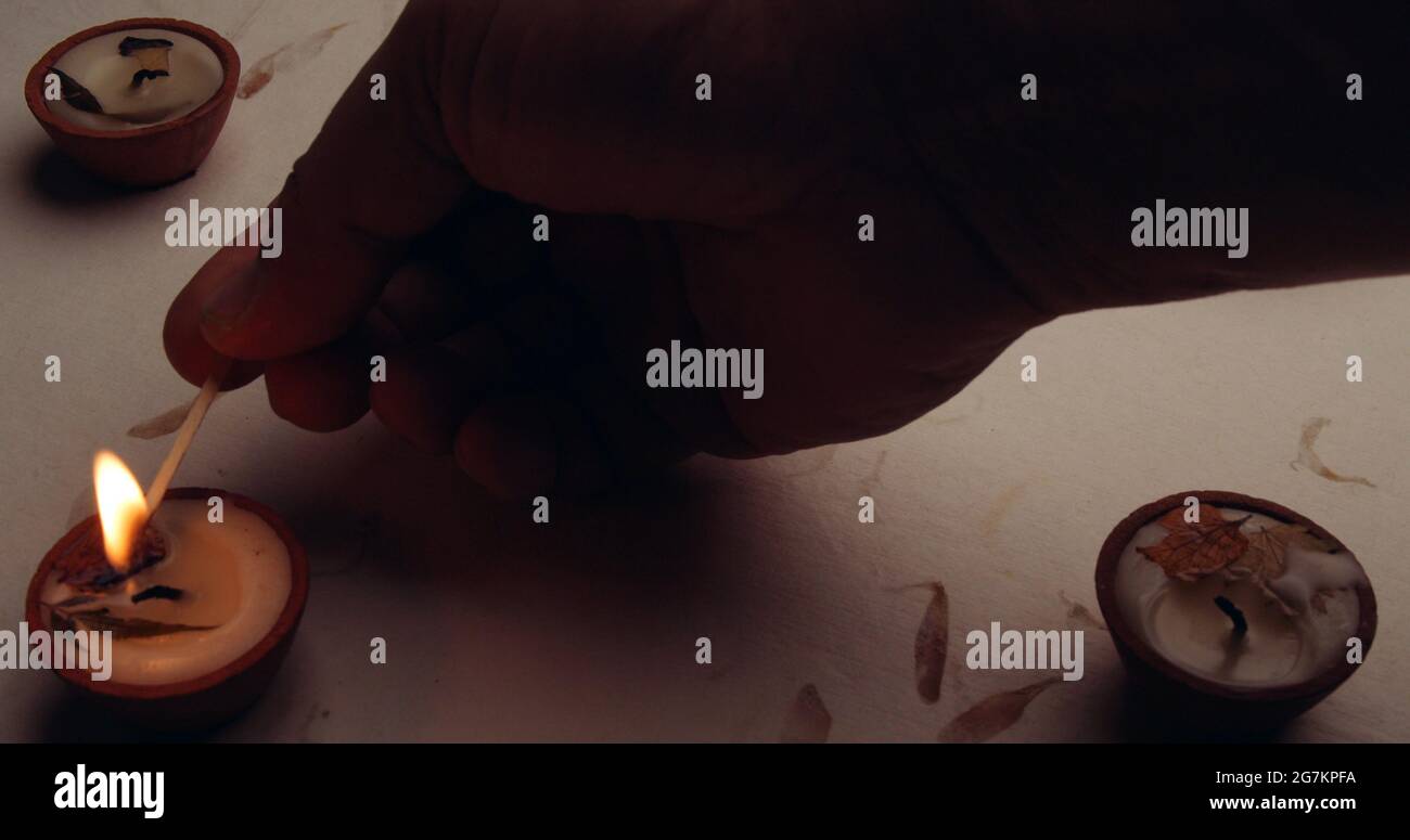 Hand lighting a candle with a matchstick; Diwali lights Stock Photo - Alamy