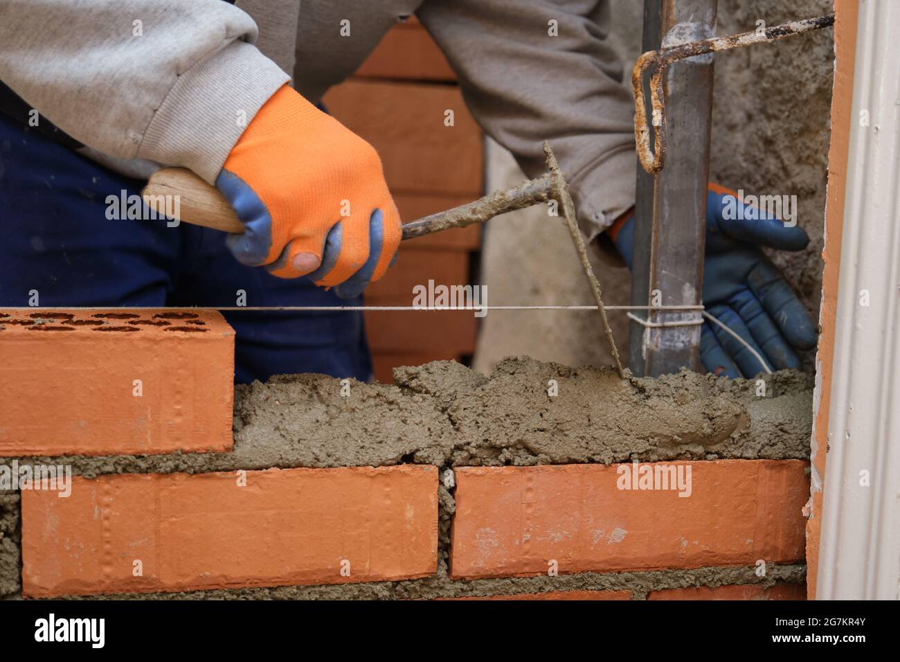 Construction worker putting cement on the brick wall. Man bricklaying ...