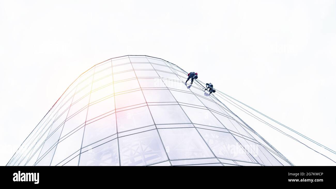 Window washer climber cleaning glass building facade Stock Photo - Alamy