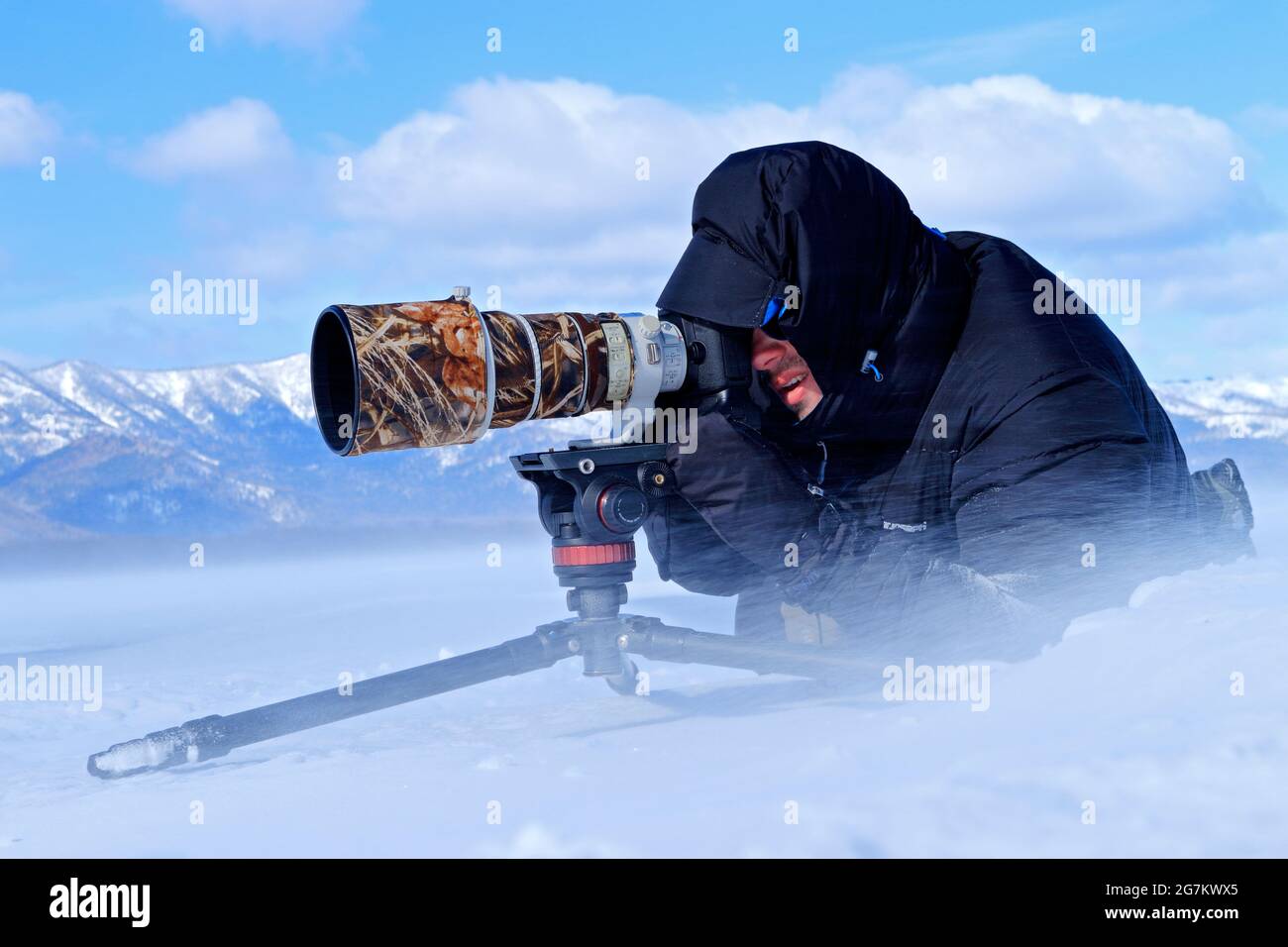 Winter photography, man in the snow with camera. Snow lake with ice in ...